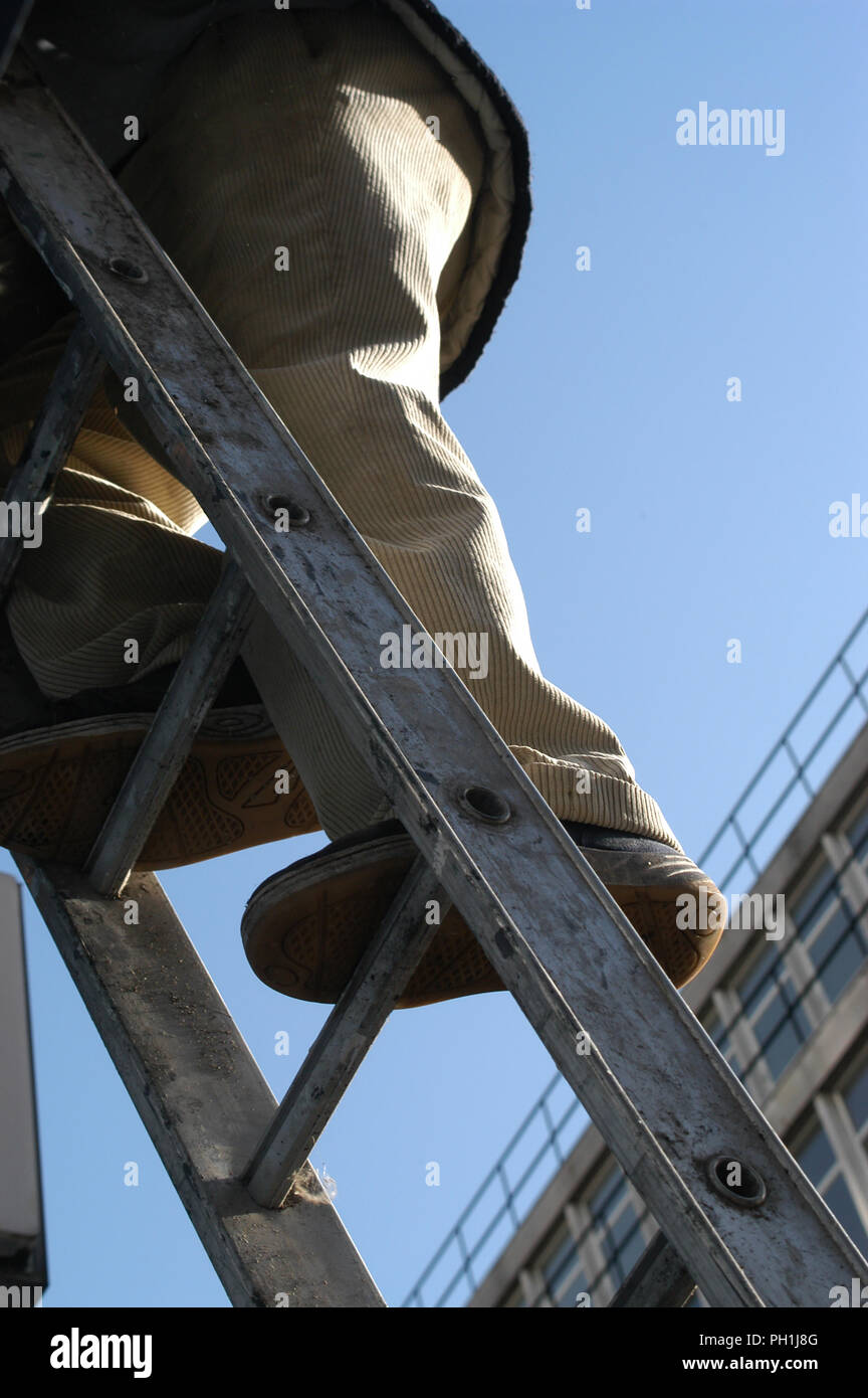 Mans feet and legs going up ladder rungs in the City area of London ...