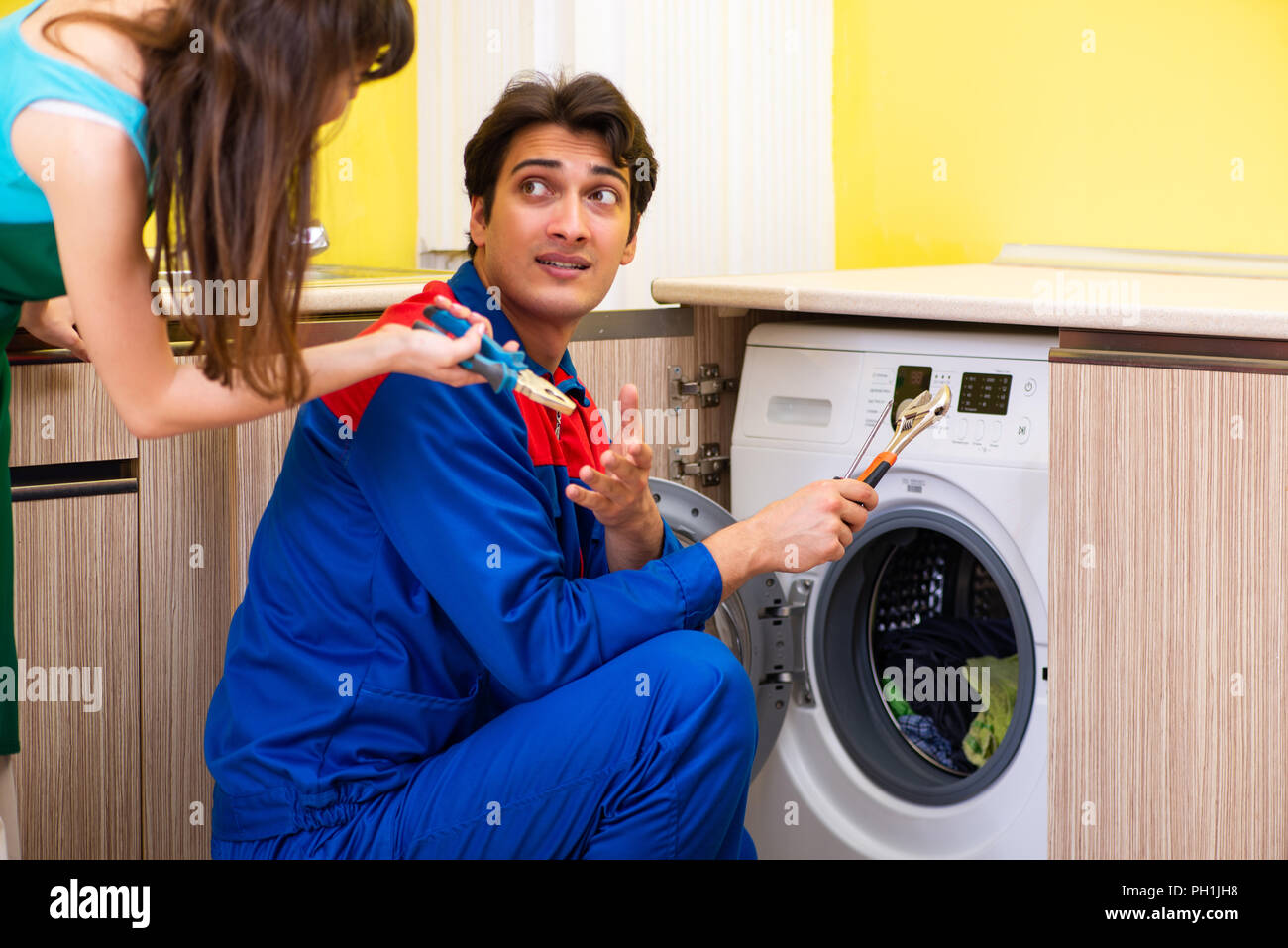 Contractor repairing washing machine at home Stock Photo - Alamy