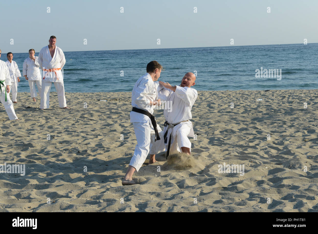 group of shotokan karatekas practicing at the beach in the morning sun ...