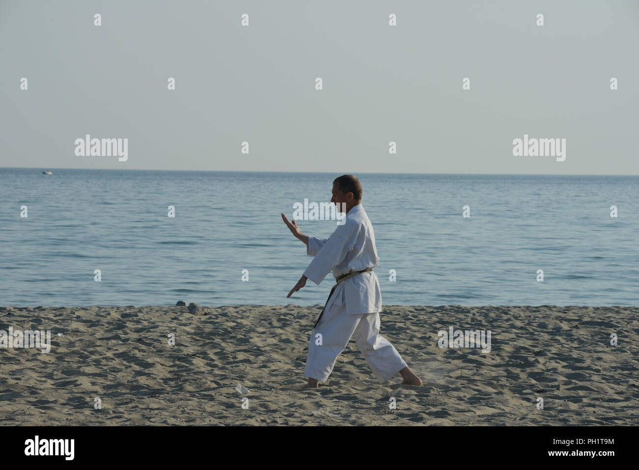 group of shotokan karatekas practicing at the beach in the morning sun ...