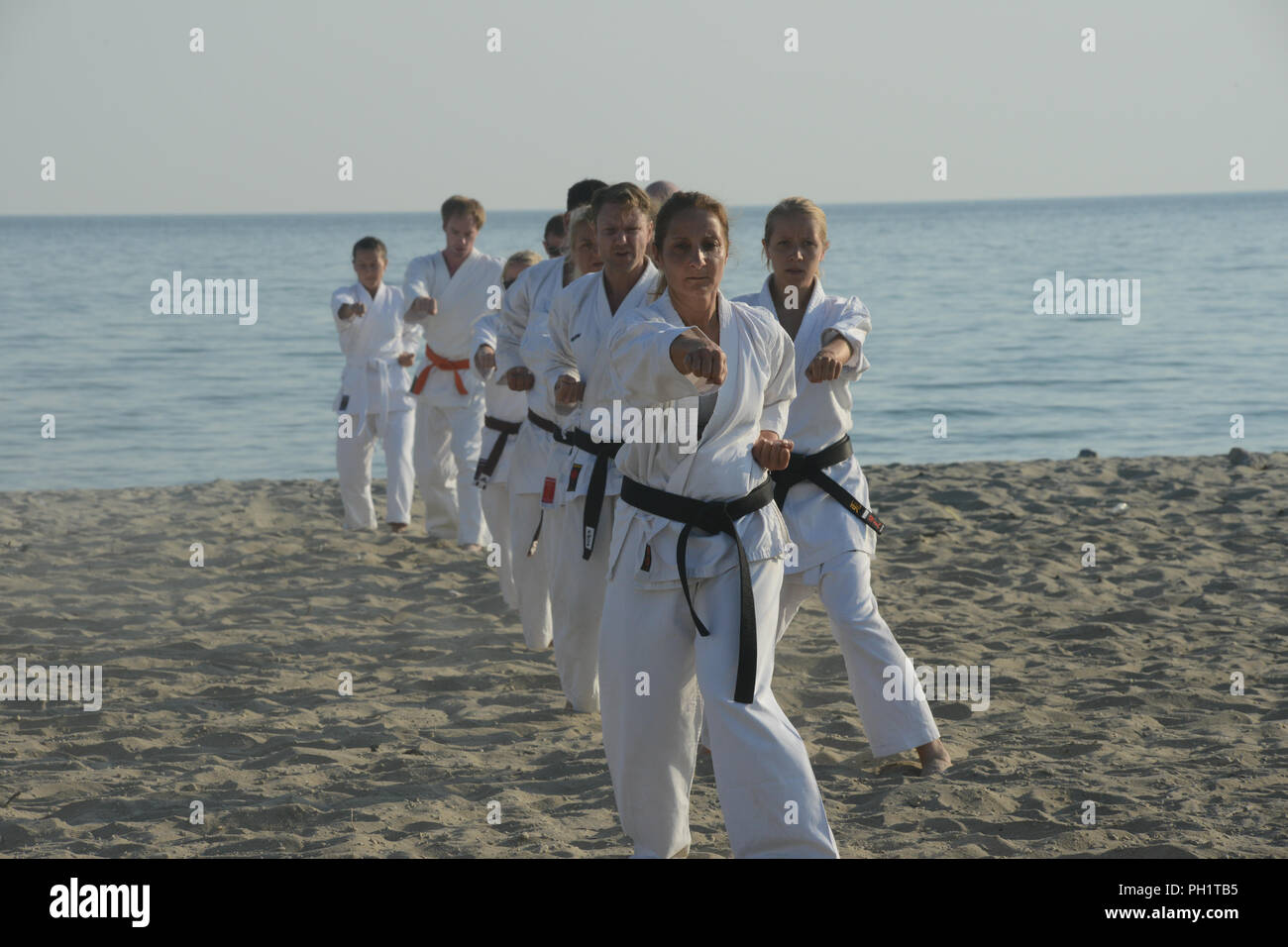group of shotokan karatekas practicing at the beach in the morning sun ...