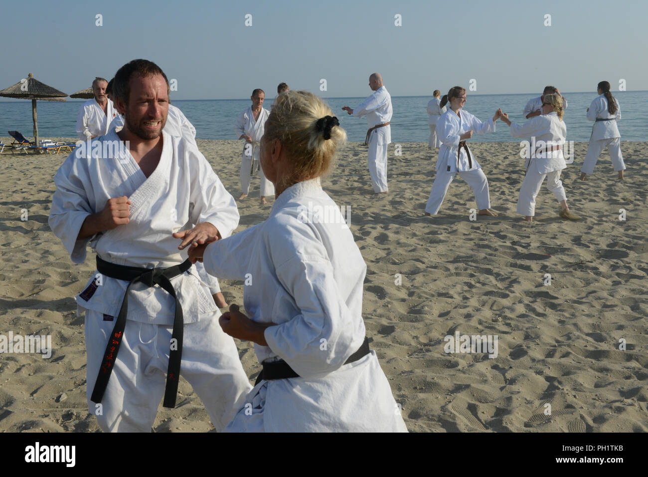 group of shotokan karatekas practicing at the beach in the morning sun ...