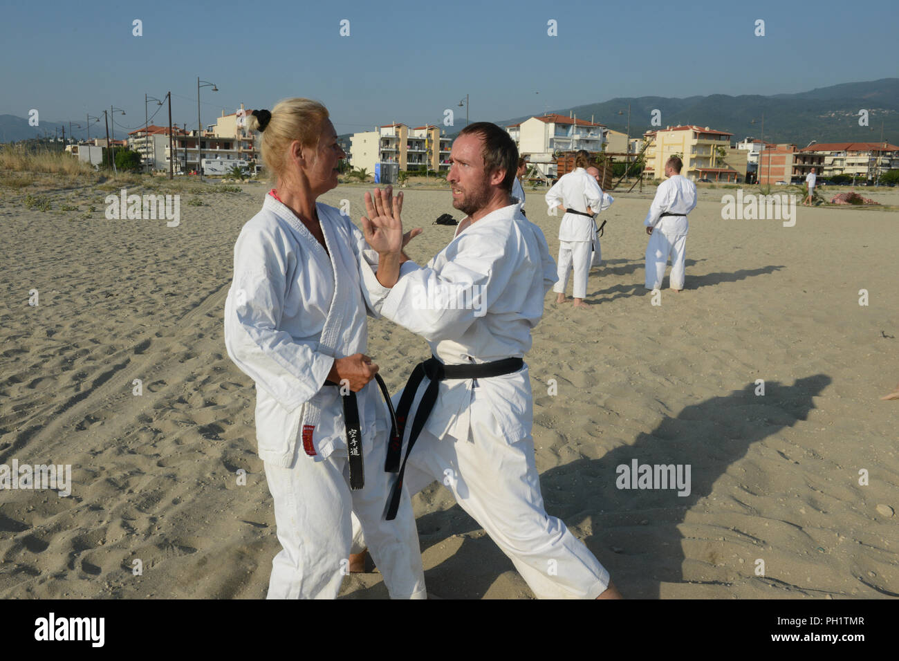 group of shotokan karatekas practicing at the beach in the morning sun ...