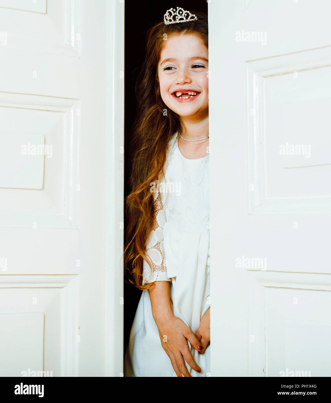 little cute girl at home, opening door well-dressed in white dre Stock ...