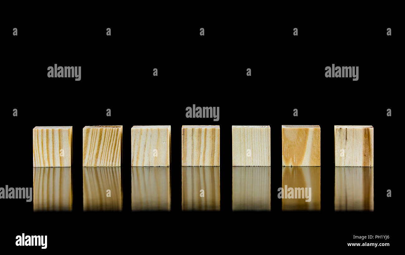 Row of seven blank wooden blocks on a black background with copyspace ...