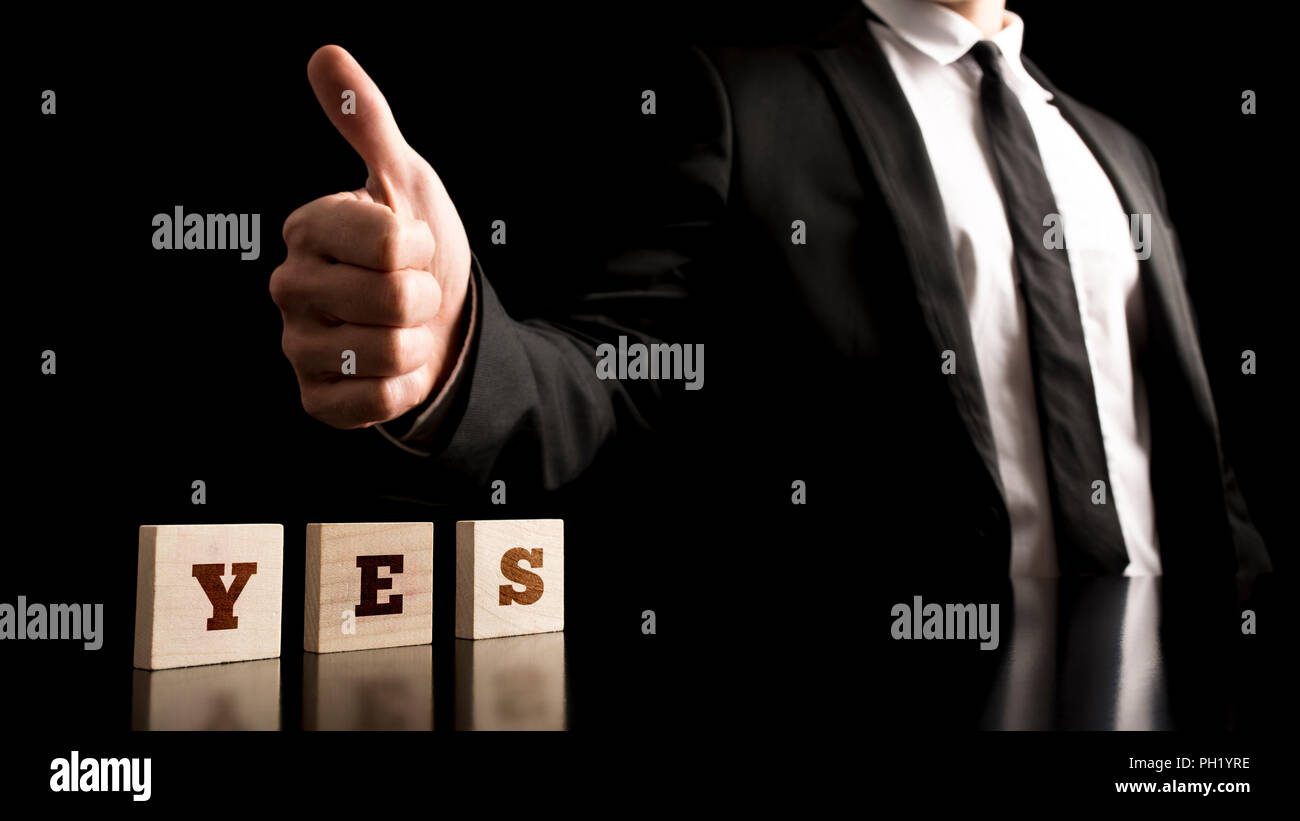 Businessman making a thumbs up gesture over a Yes sign. Conceptual of ...