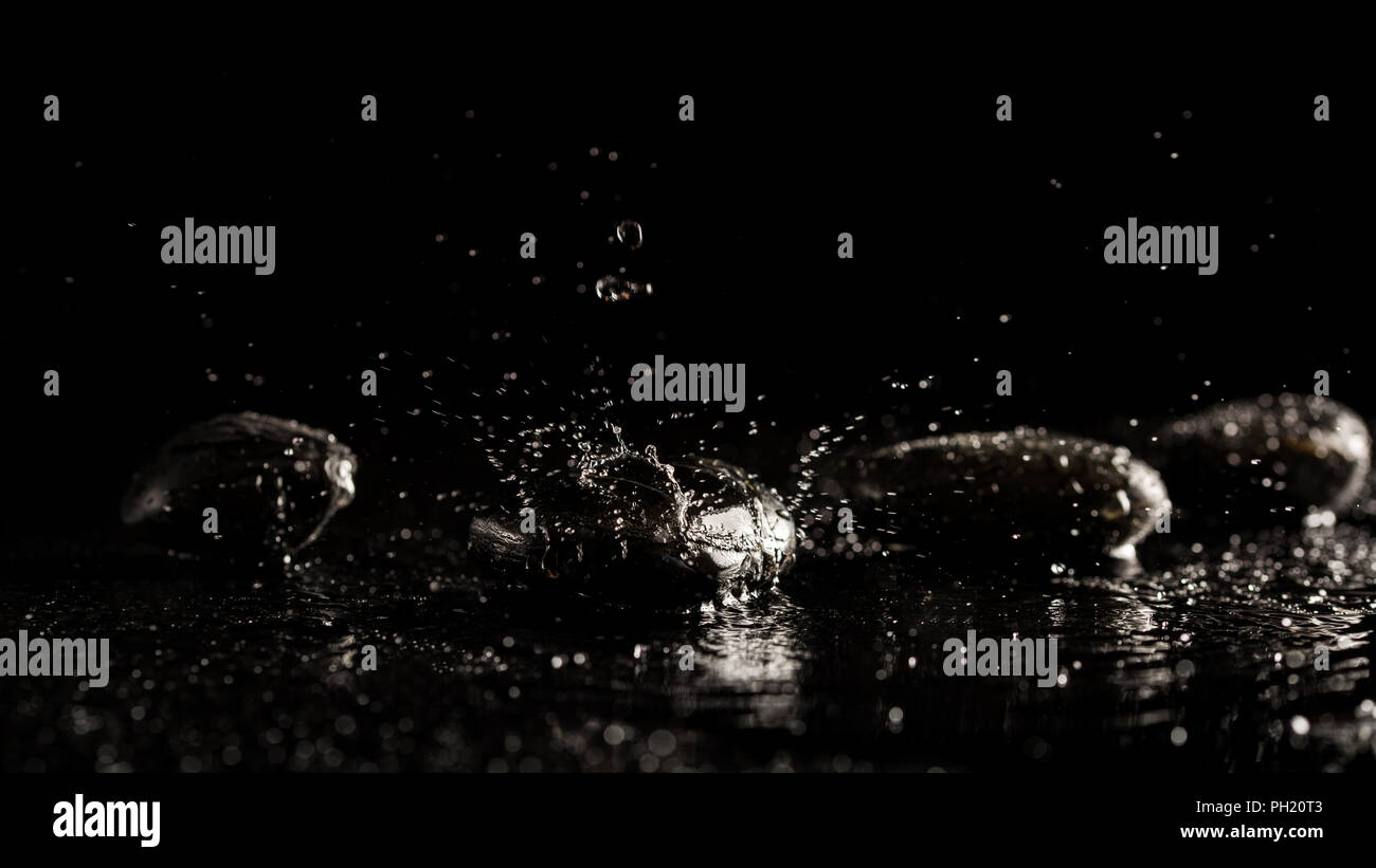 Dark atmospheric image of pure fresh water splashing on smooth black ...