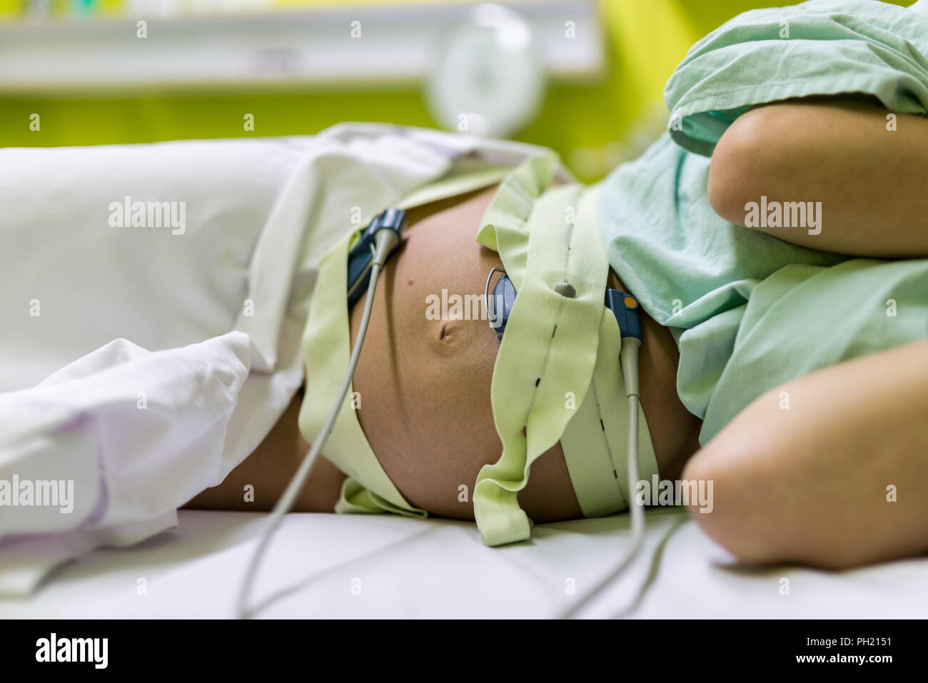 Pregnant woman undergoing cardiotocography to monitor the contractions ...