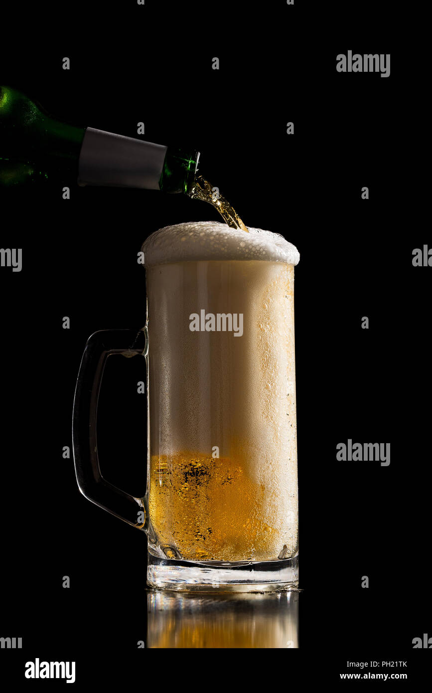 Pouring a glass tankard of beer or lager with a frothy head from a ...