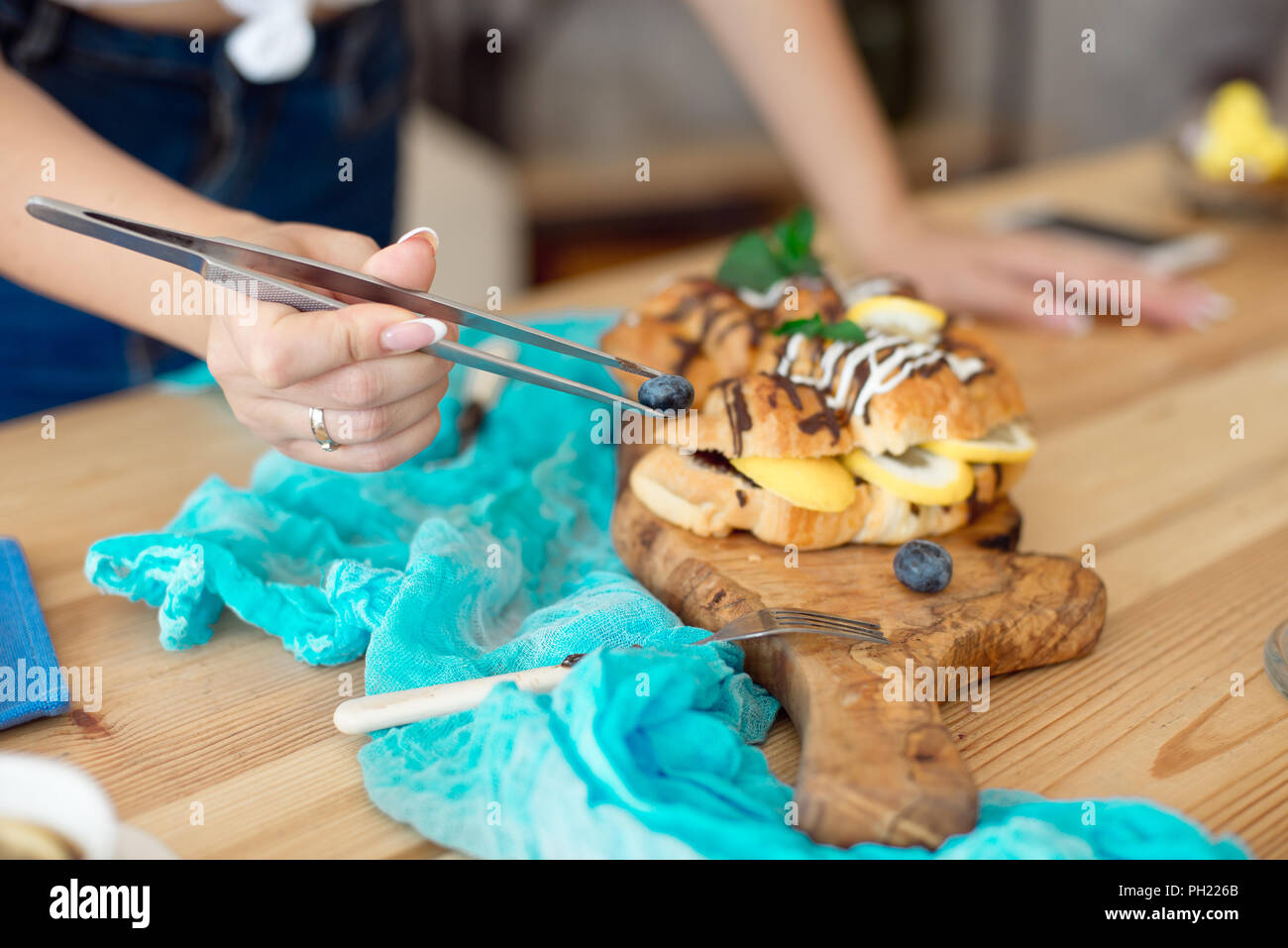 Close-up chef decorating sweet croissant on cooking table ...