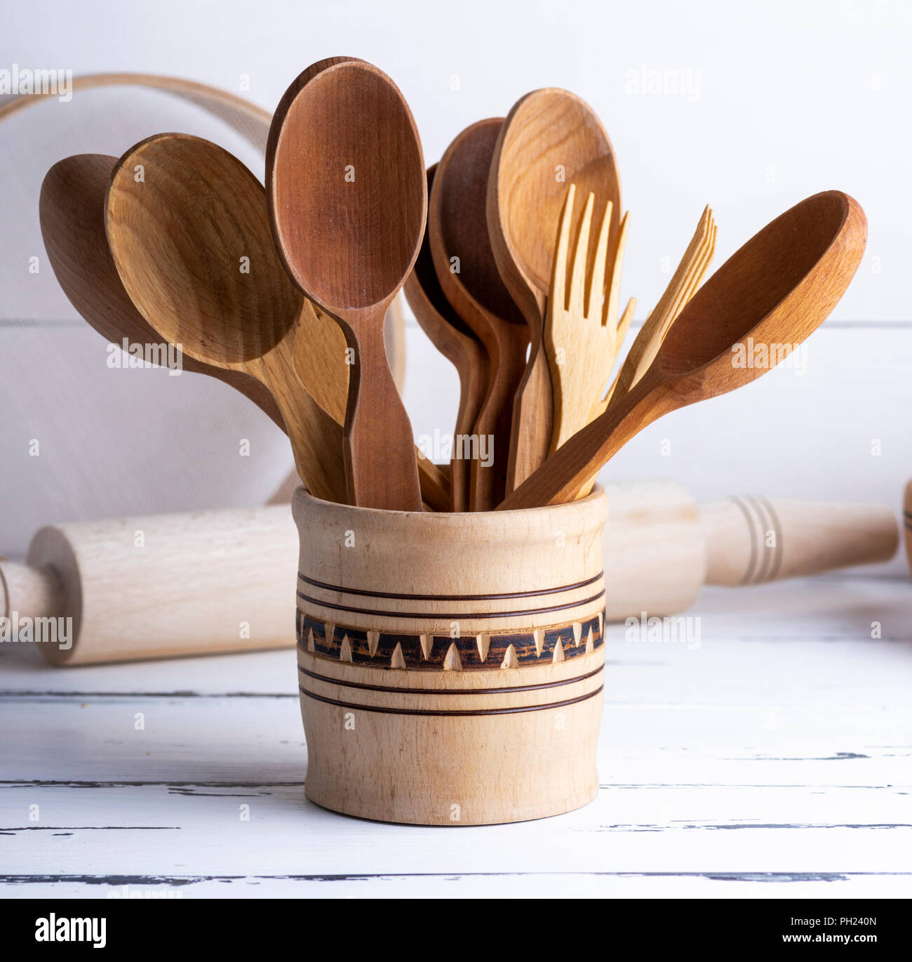 various wooden objects in a wooden jar, spoons, forks, rolling pin ...