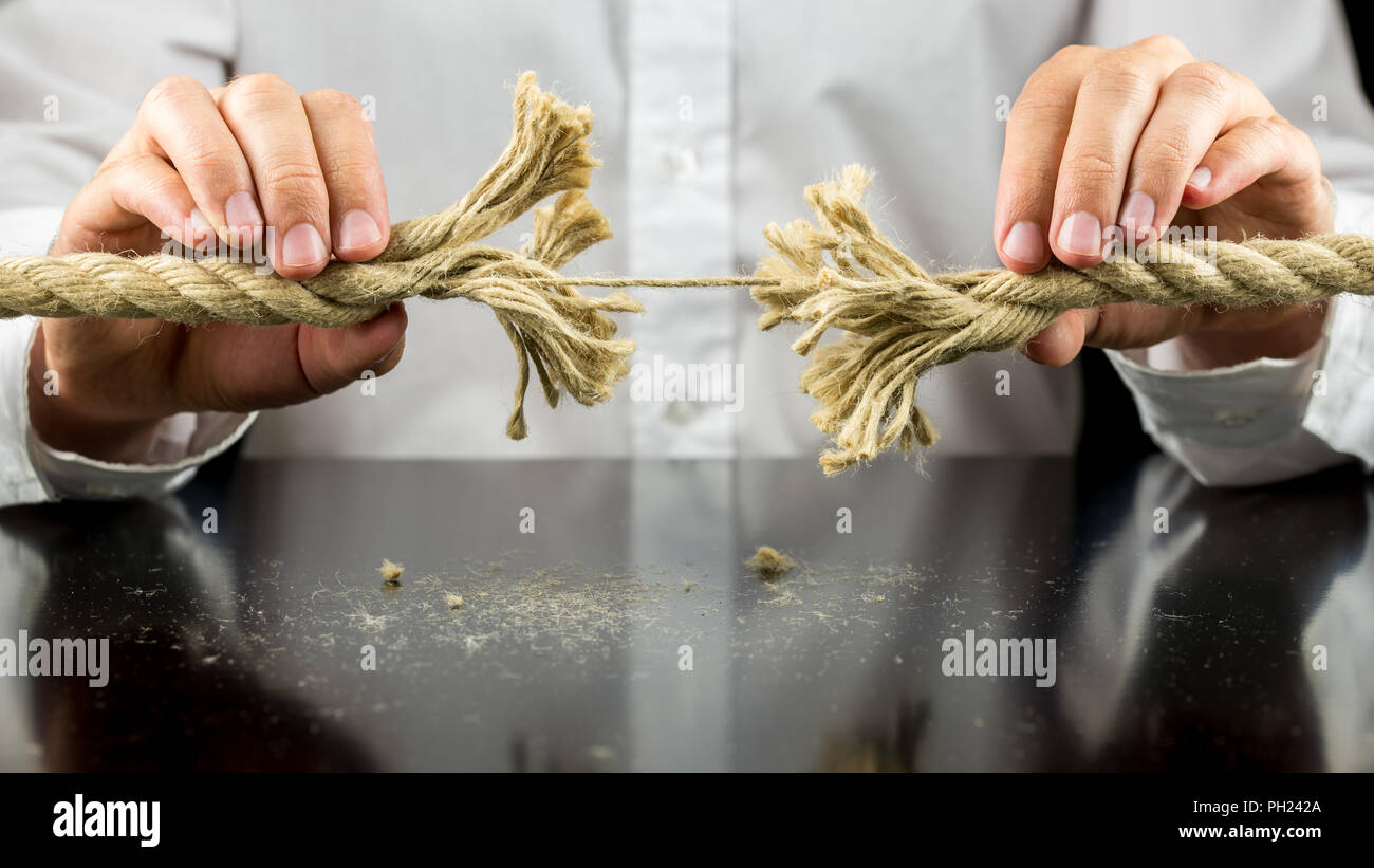 Man holding a frayed rope with one remaining string intact in both his ...