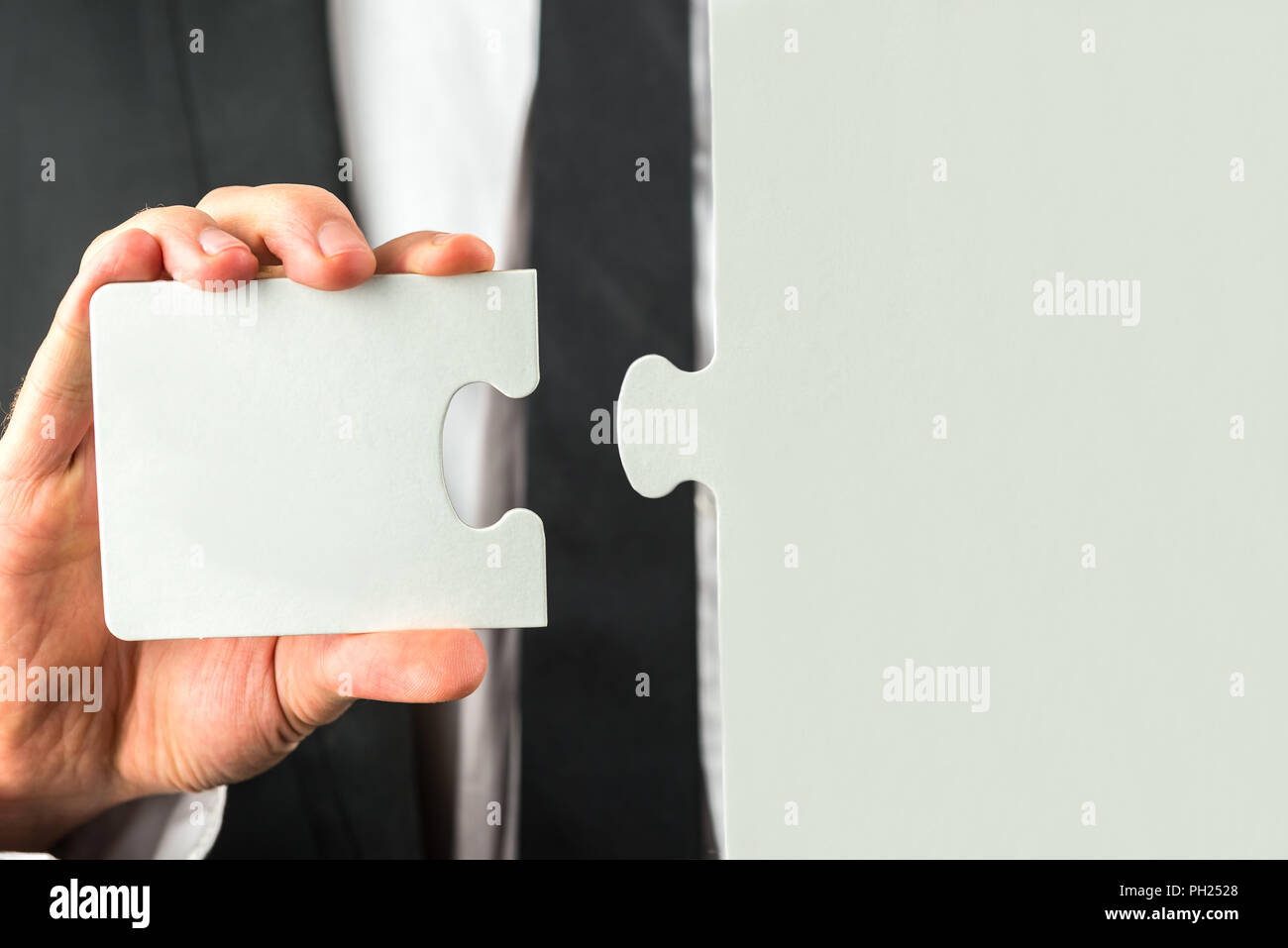 Businessman holding the missing piece to complete the puzzle in his ...