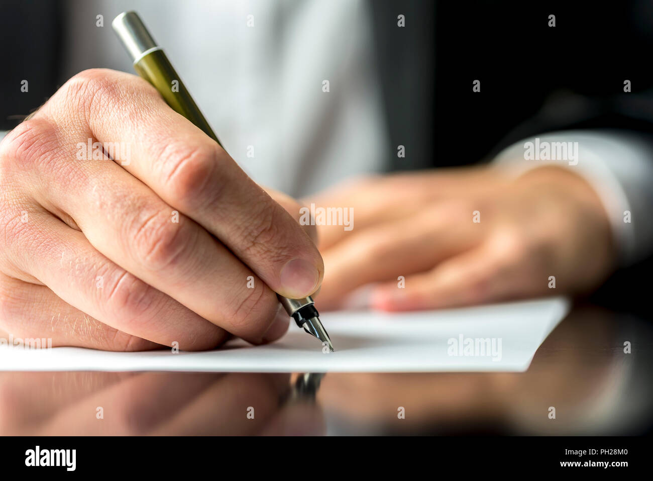 Close up of the hands of a businessman in a suit signing or writing a ...