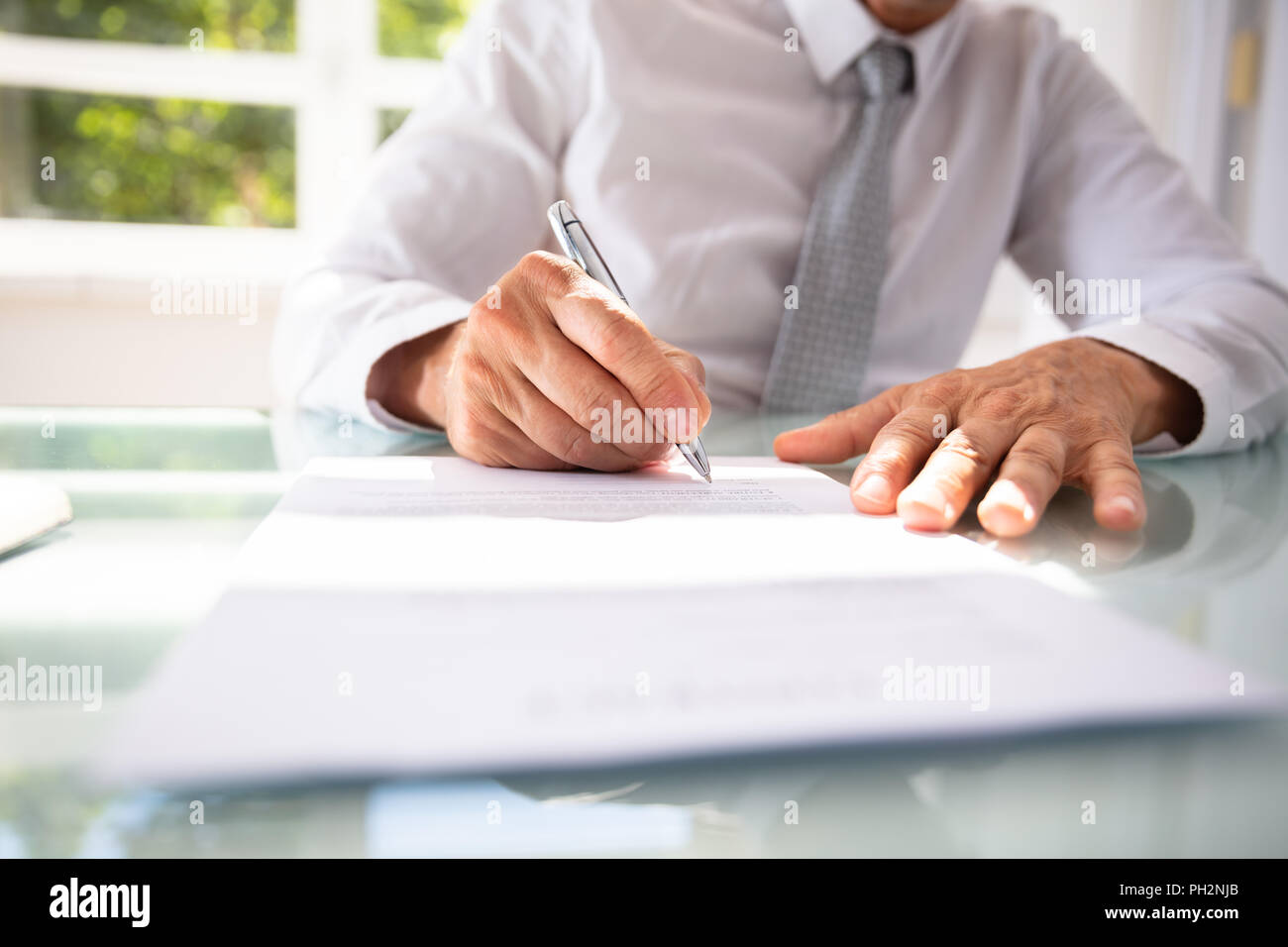 Businessman's Hand Filling Contract Form With Pen Stock Photo - Alamy