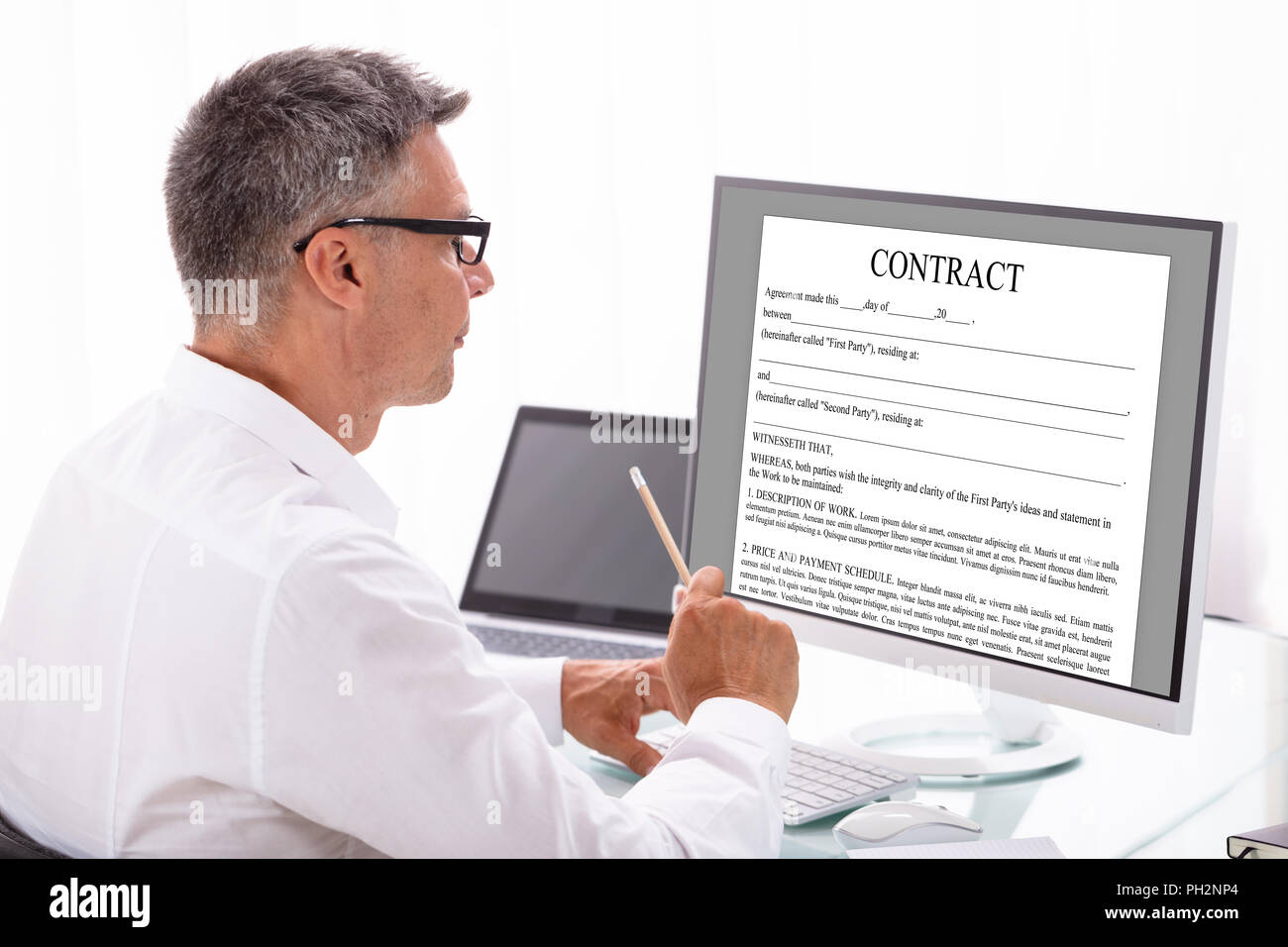 Mature Businessman Reading Contract On Computer At Workplace Stock ...
