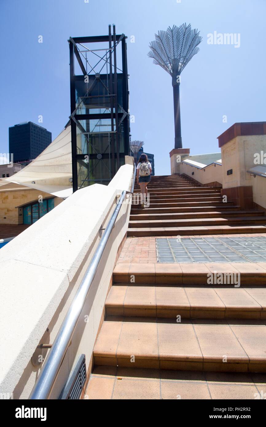 A woman walks up an elaborate staircase under bright sun in Civic ...