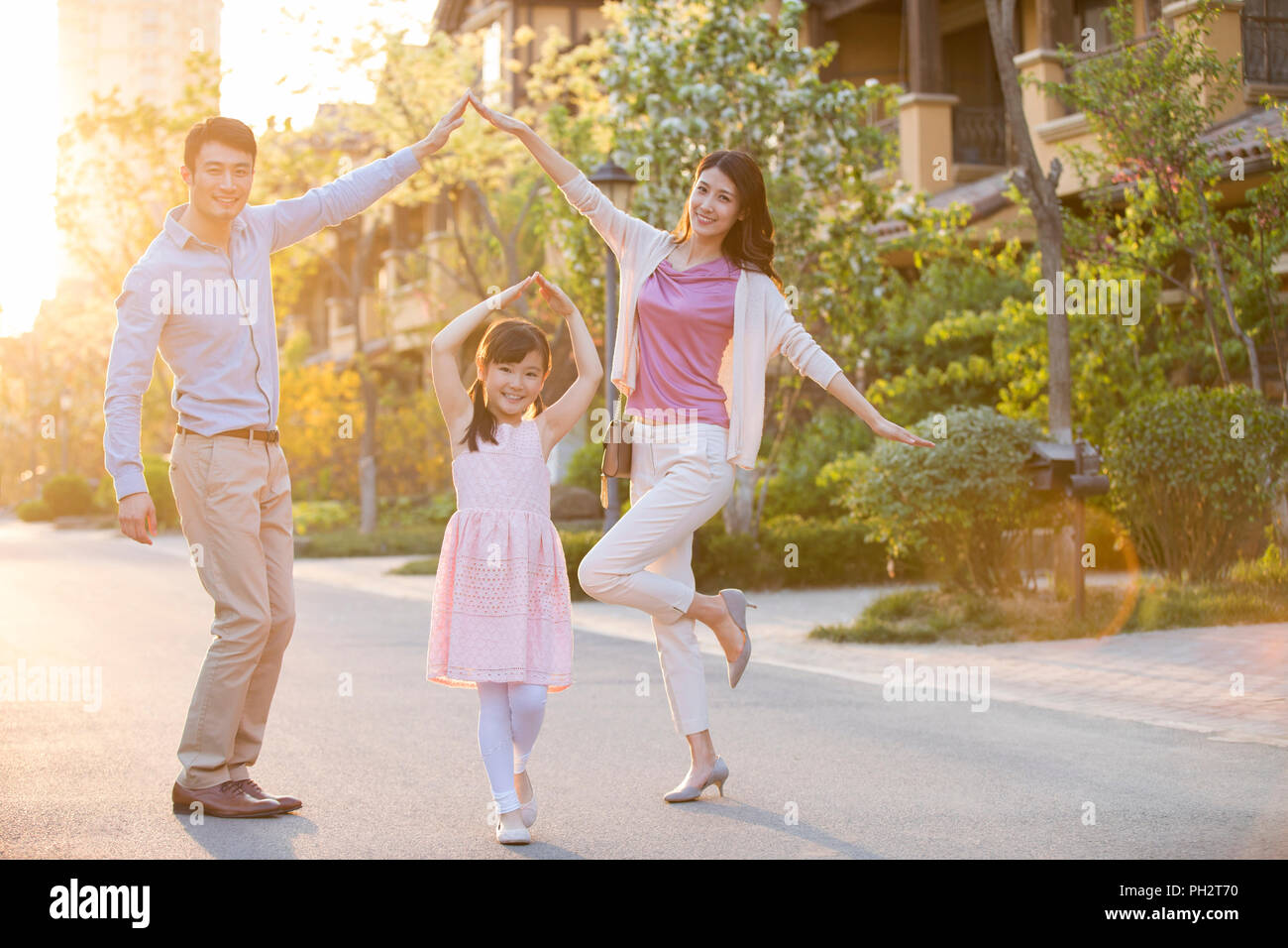 Happy young family standing in front of their new house Stock Photo - Alamy