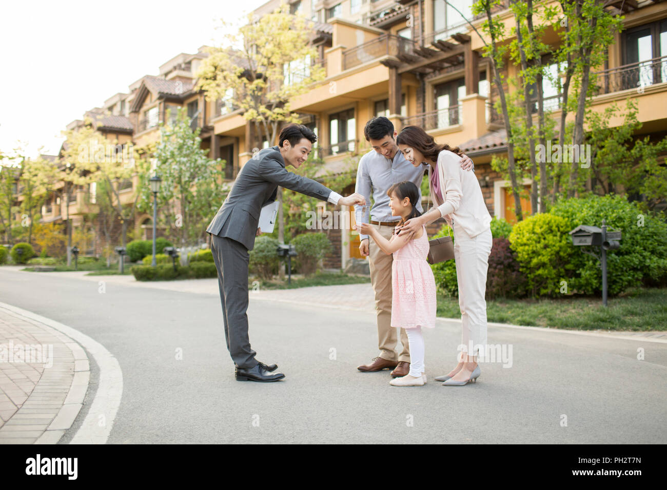 Realtor giving young family keys to new house Stock Photo - Alamy