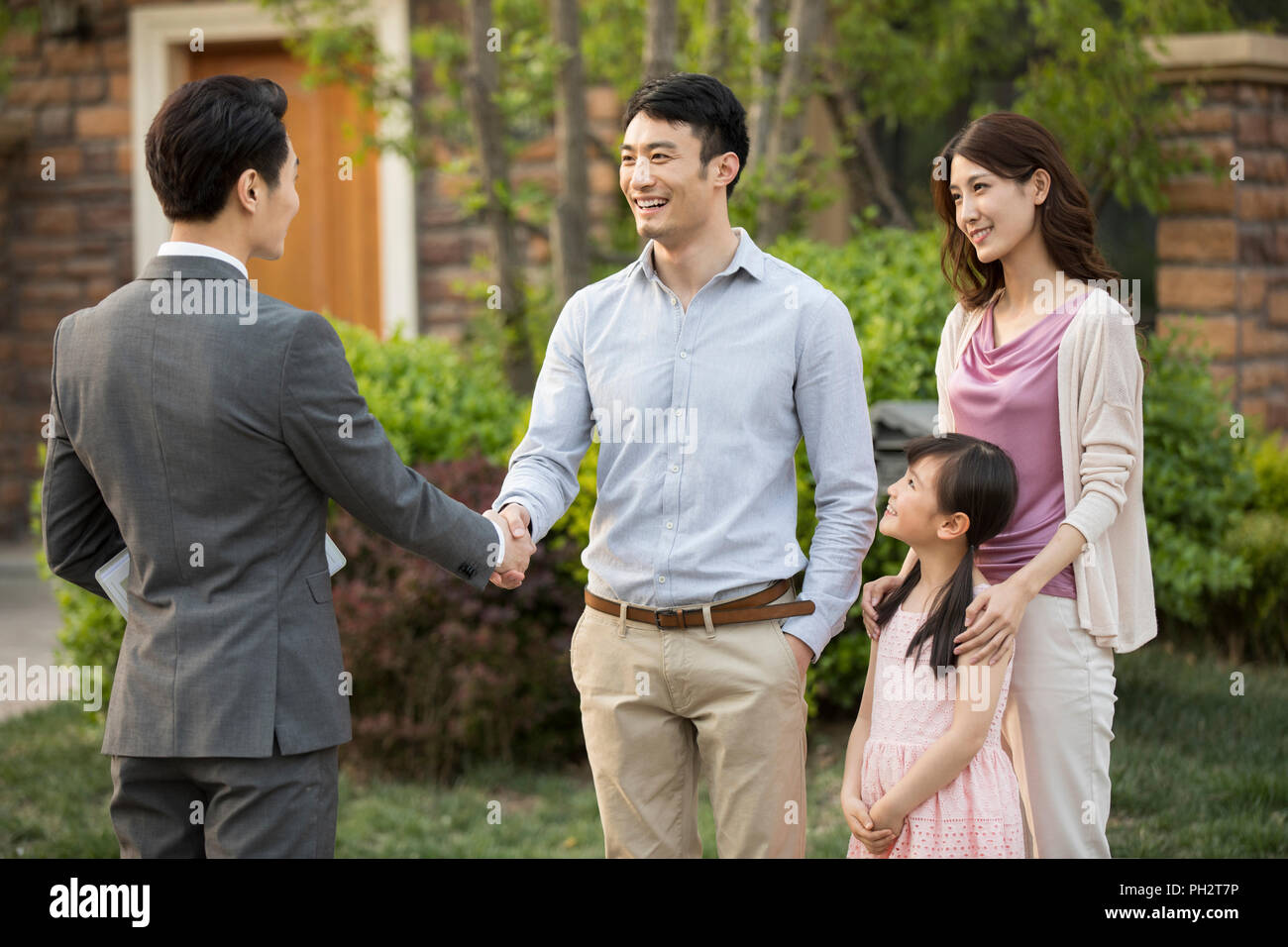 Happy young family shaking hands with realtor Stock Photo - Alamy