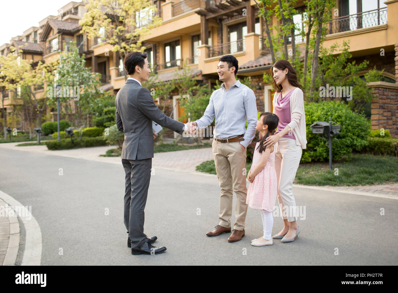 Happy young family shaking hands with realtor Stock Photo - Alamy