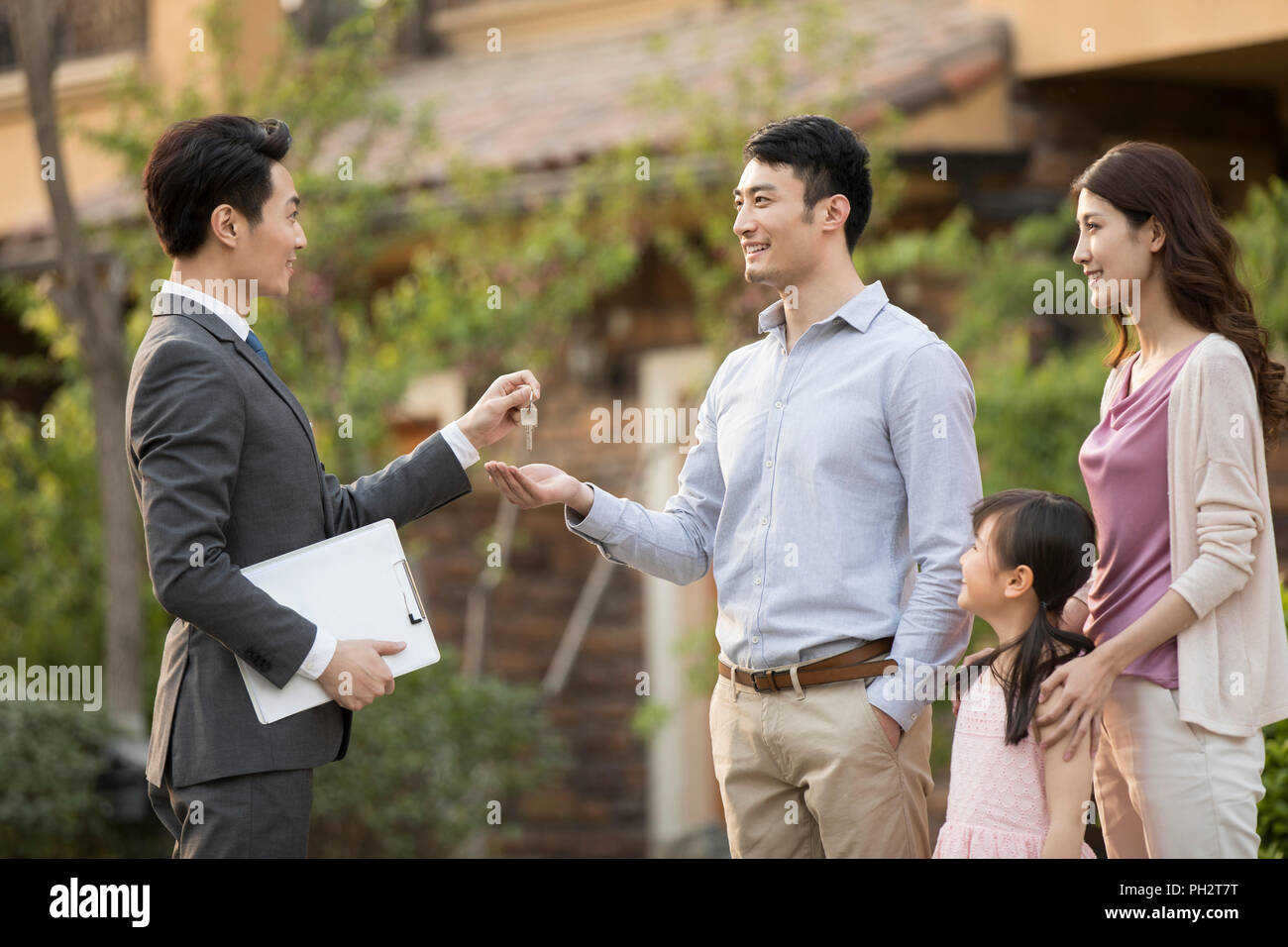 Realtor giving young family keys to new house Stock Photo - Alamy