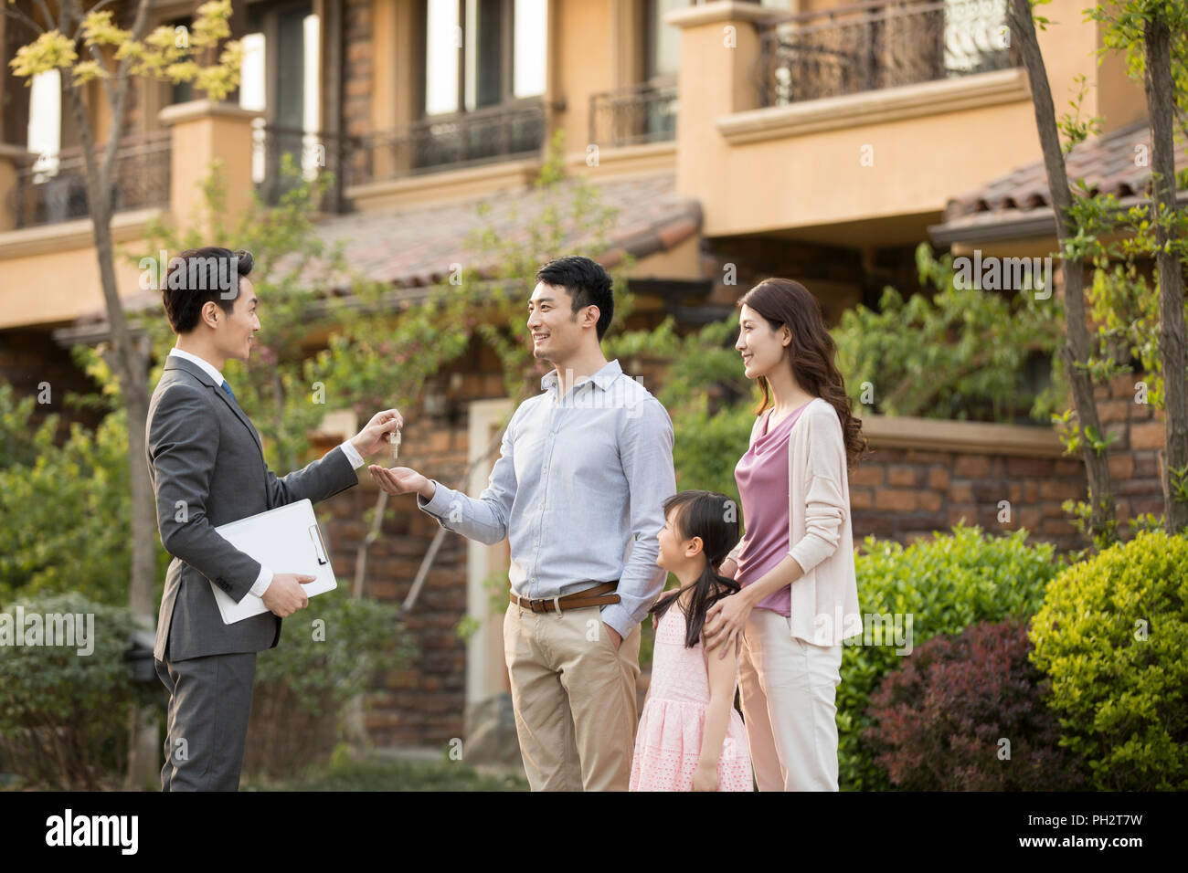 Realtor giving young family keys to new house Stock Photo - Alamy