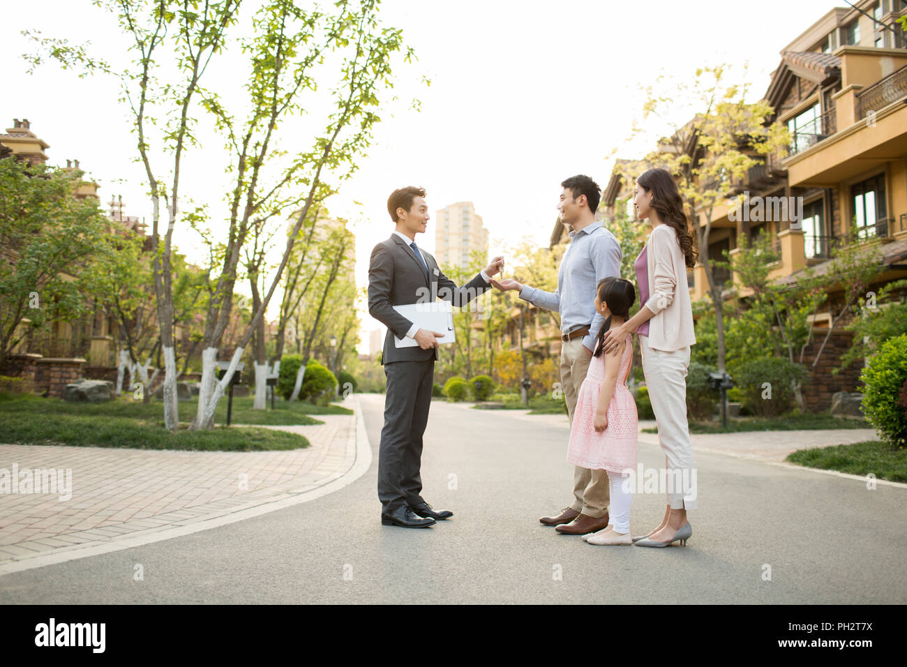 Realtor giving young family keys to new house Stock Photo - Alamy
