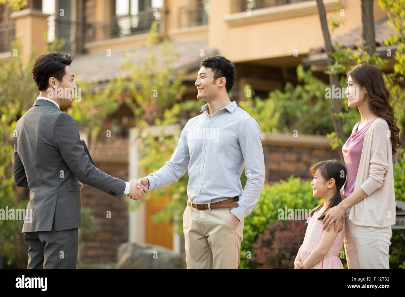 Happy young family shaking hands with realtor Stock Photo - Alamy