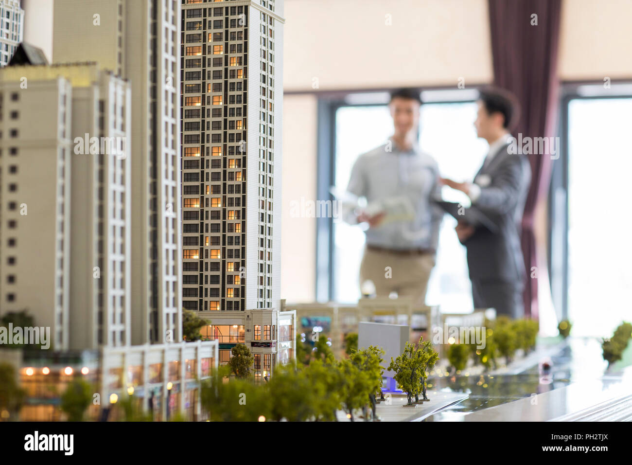 Realtor showing architectural model to young man Stock Photo - Alamy