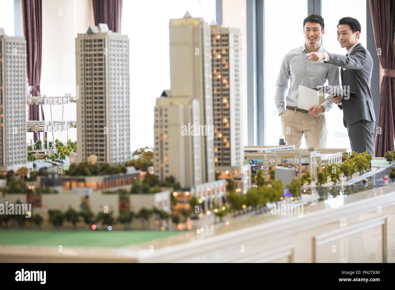 Realtor showing architectural model to young man Stock Photo - Alamy