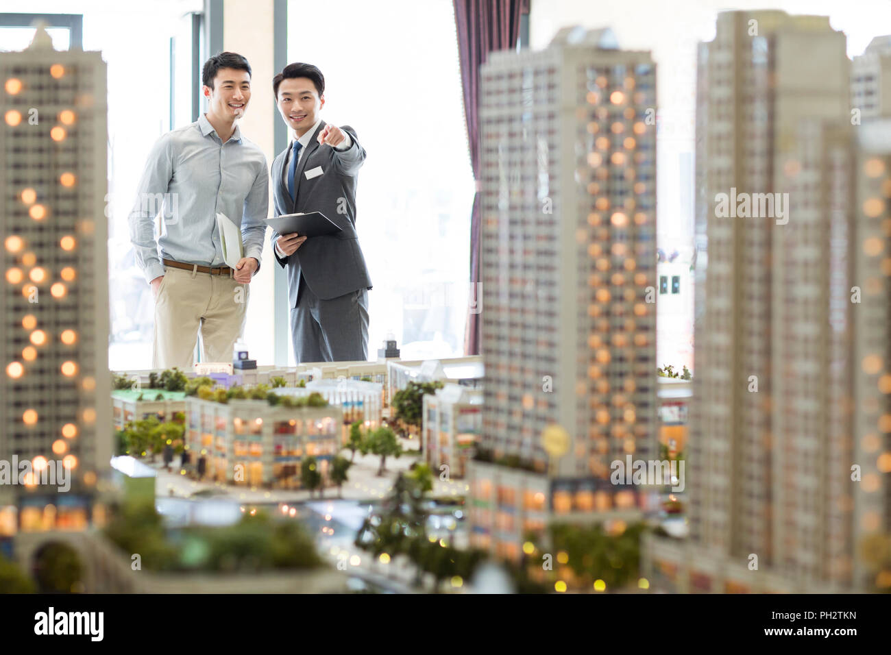 Realtor showing architectural model to young man Stock Photo - Alamy