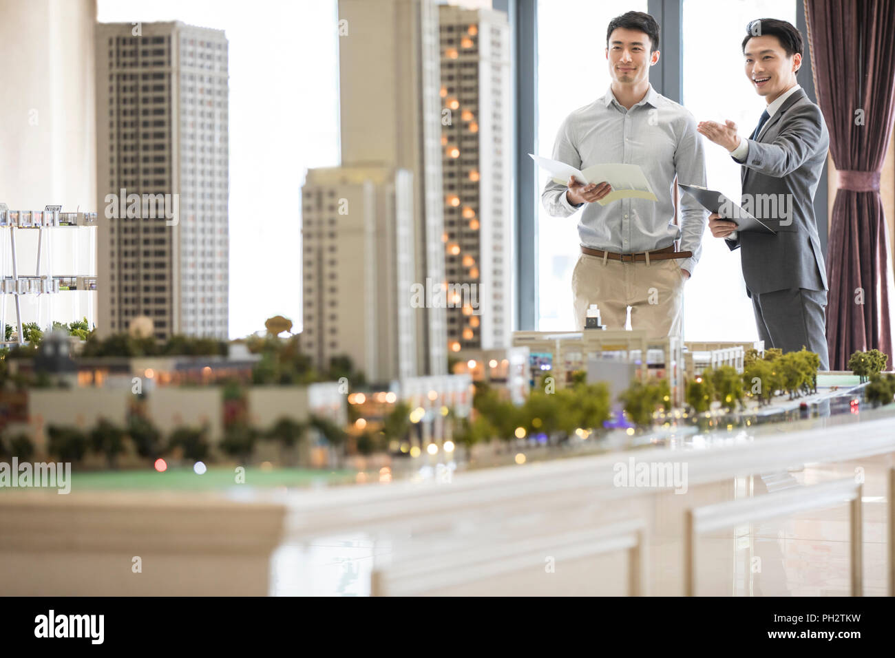 Realtor showing architectural model to young man Stock Photo - Alamy