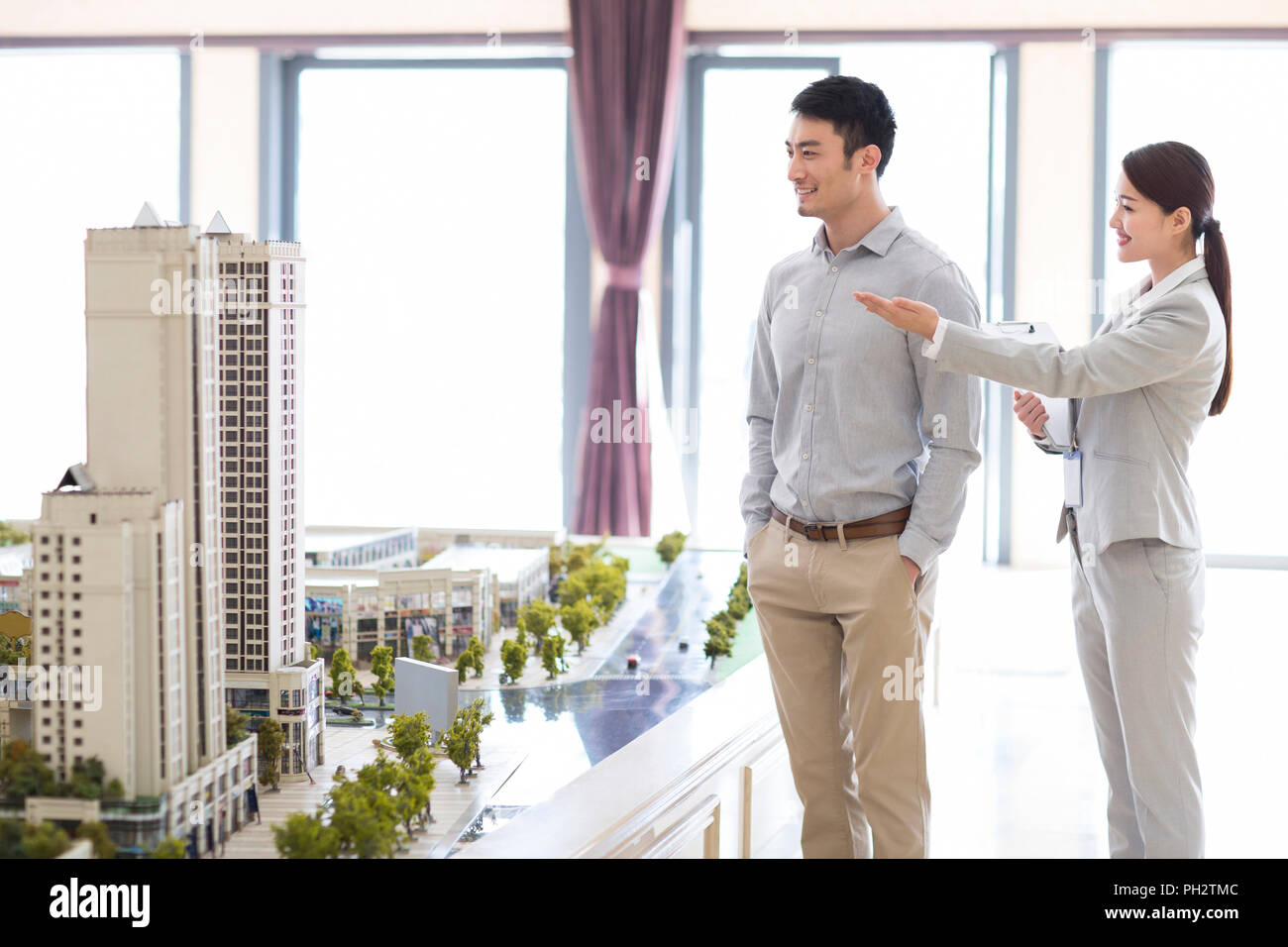 Realtor showing architectural model to young man Stock Photo - Alamy