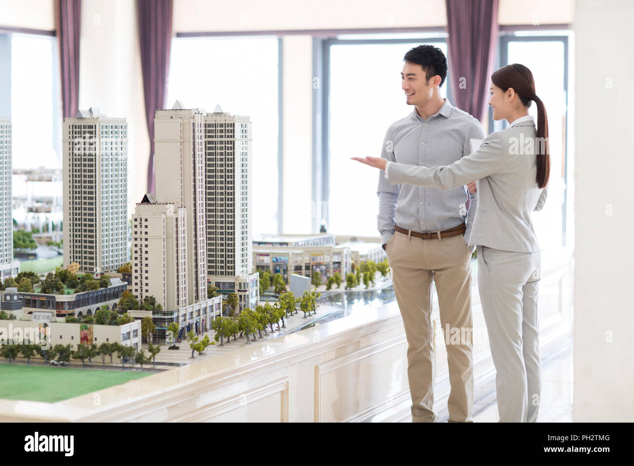 Realtor showing architectural model to young man Stock Photo - Alamy