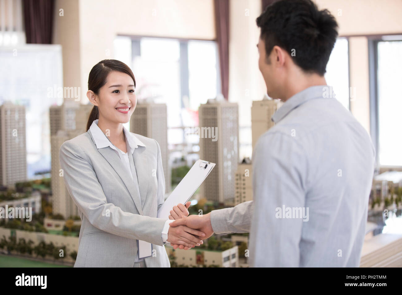 Confident realtor shaking hands with customer Stock Photo - Alamy