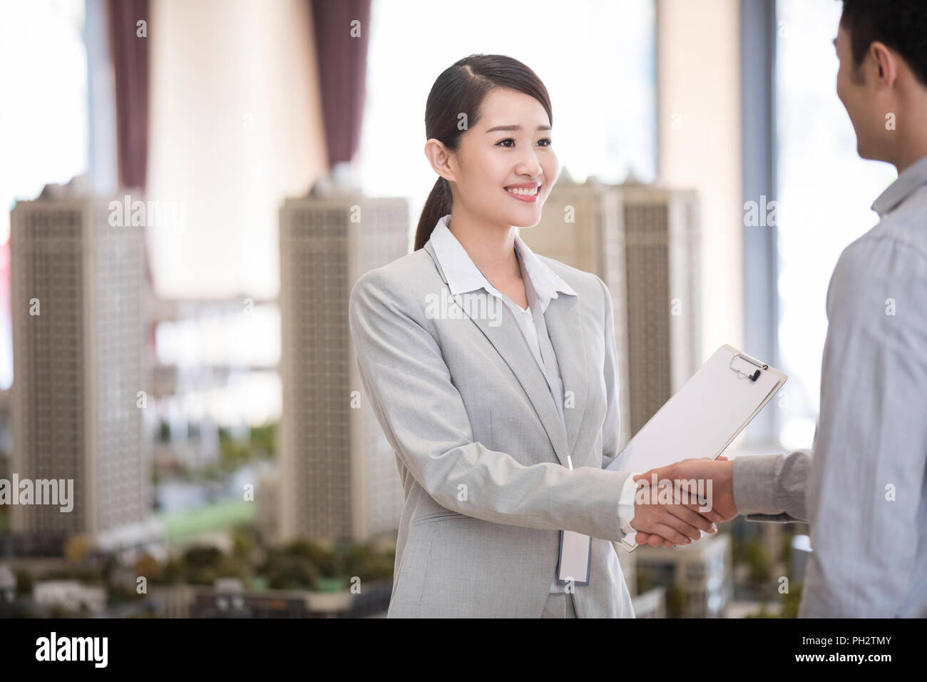 Confident realtor shaking hands with customer Stock Photo - Alamy