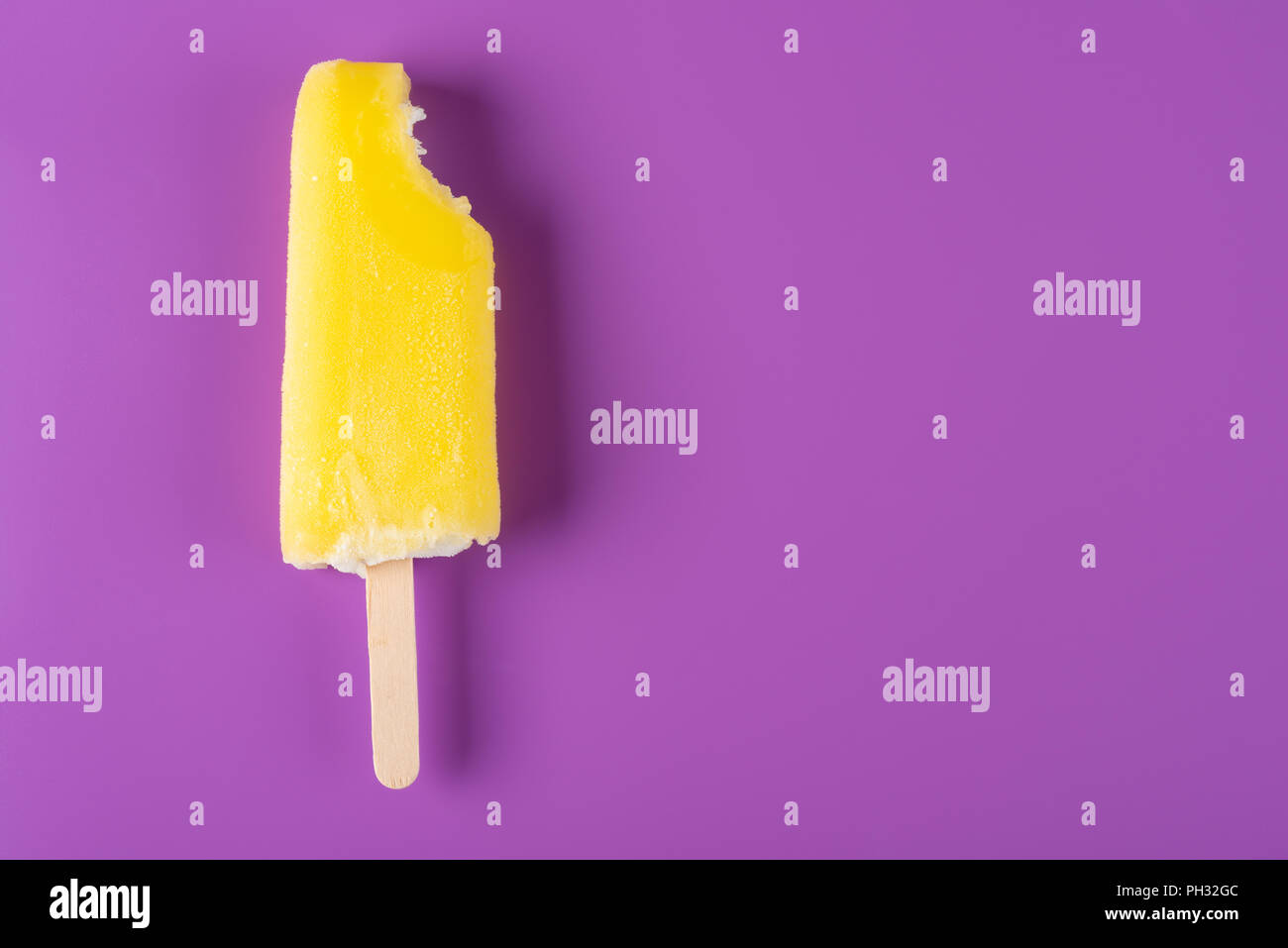 yellow popsicle with a bite on a purple background Stock Photo - Alamy