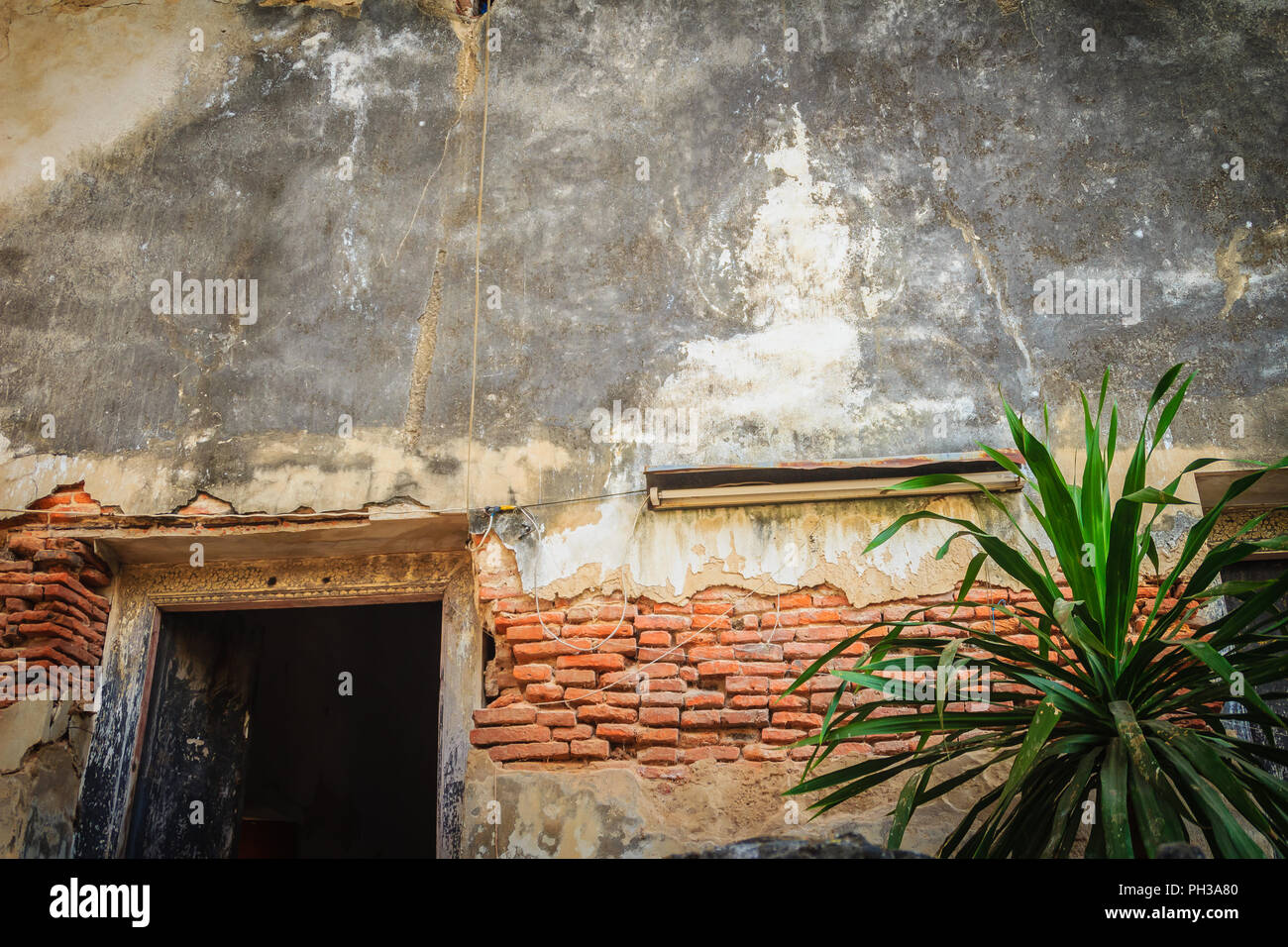 Gable end of an old buddhist church with old door and grungy brick wall ...