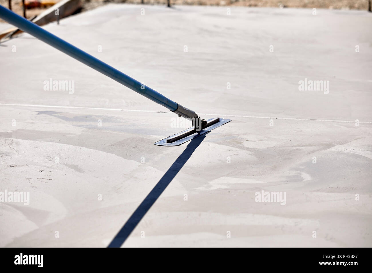 A mason finishing a newly poured concrete slab with a smooth finish and ...