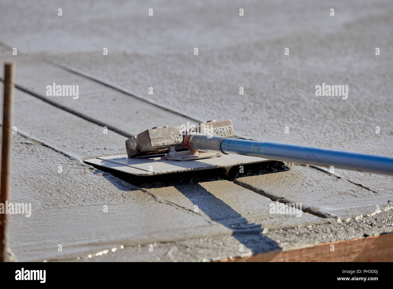A mason using a concrete groover with a weight on it to finish a newly ...