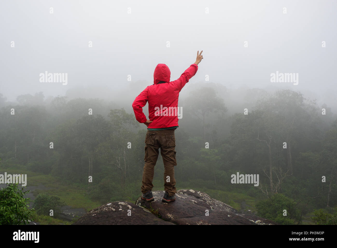 man standing on cliff with hand raised Stock Photo - Alamy