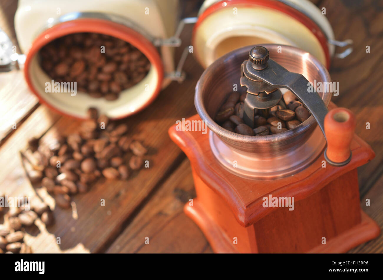 Clay pot with coffee beans and a manual coffee grinder on wooden boards ...