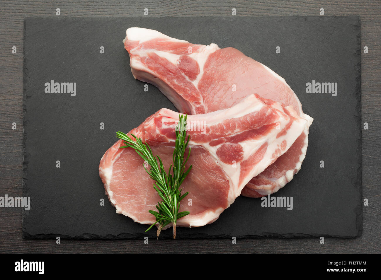 fresh raw meat with rosemary on black slate, on dark background, pork ...
