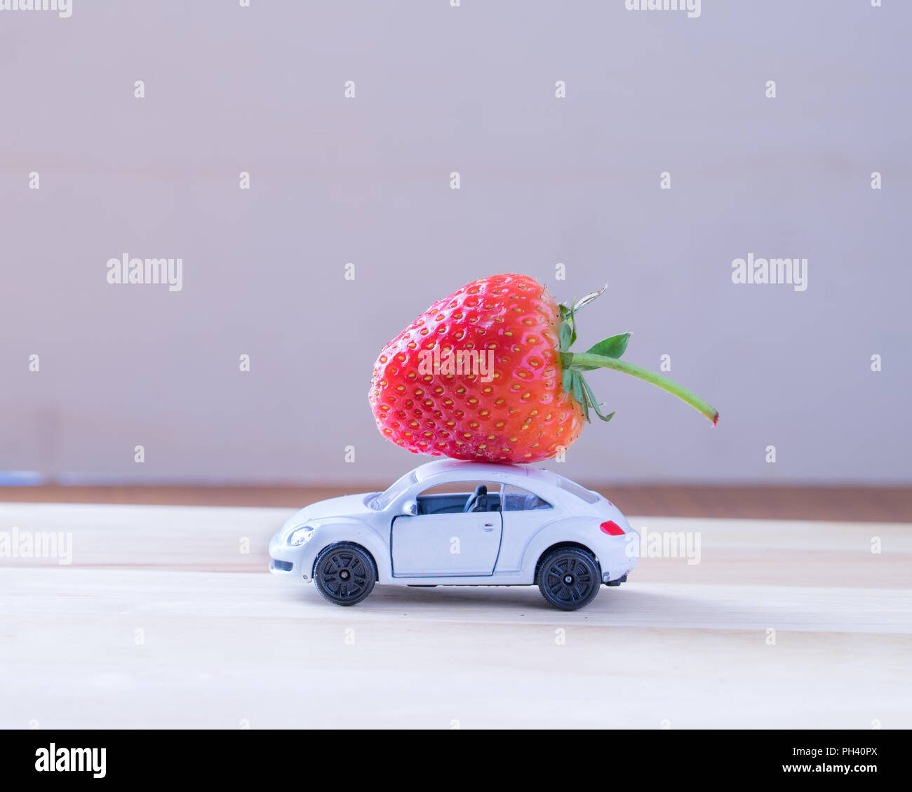 Strawberry in white toy car on white wooden background Stock Photo - Alamy