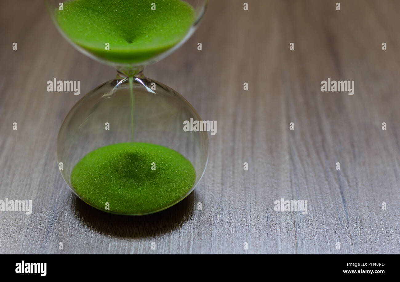 Modern hourglass or timer with green sand Stock Photo - Alamy