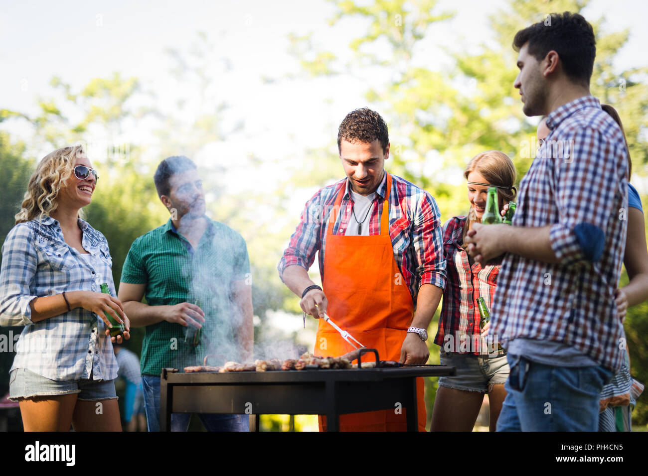 Happy students having barbecue on summer day Stock Photo - Alamy