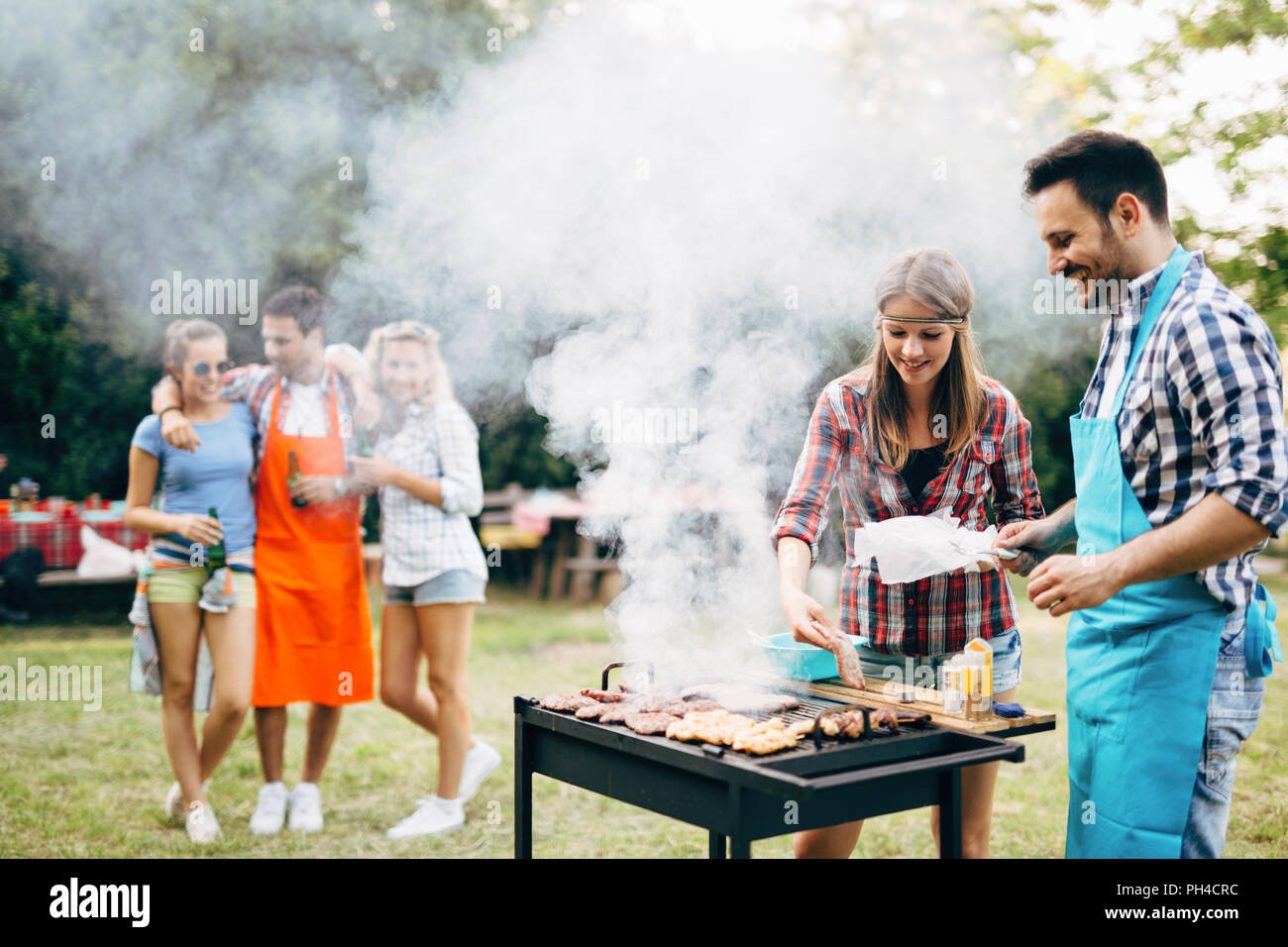 Happy students having barbecue on summer day Stock Photo - Alamy