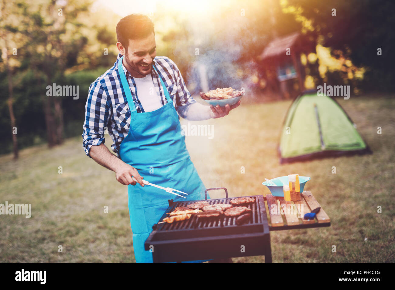 Handsome male preparing barbecue Stock Photo - Alamy