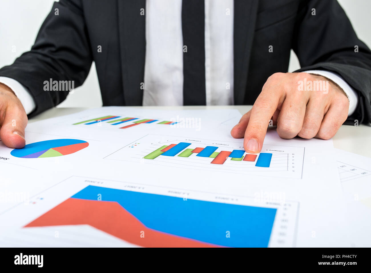 Businessman analysing a set of bar graphs as he sits at his desk ...